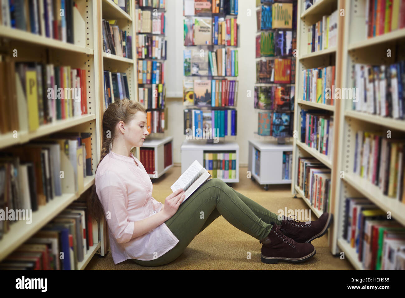 Curious teenager reading book in library Stock Photo - Alamy