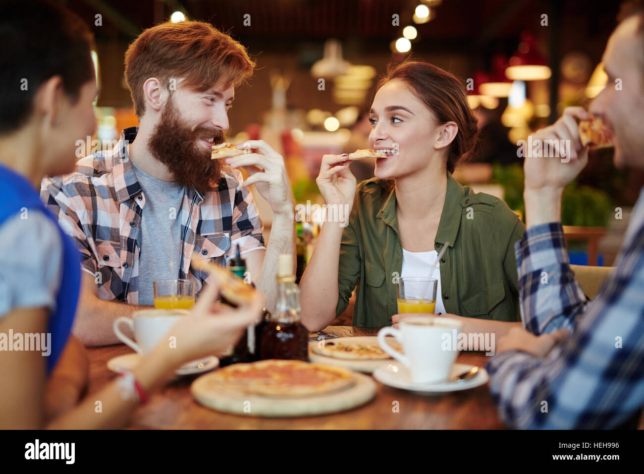 Happy friends eating tasty pizza and talking Stock Photo - Alamy
