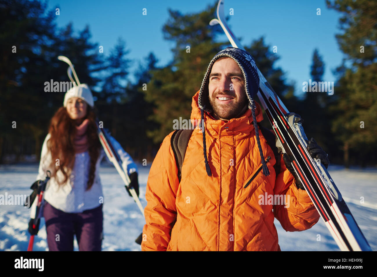 Active man and woman with skis going back home after skiing Stock Photo ...