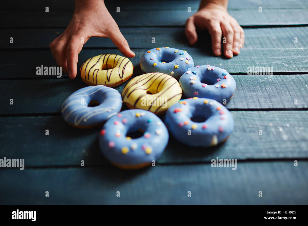 Human hand taking one sweet donut from table Stock Photo - Alamy