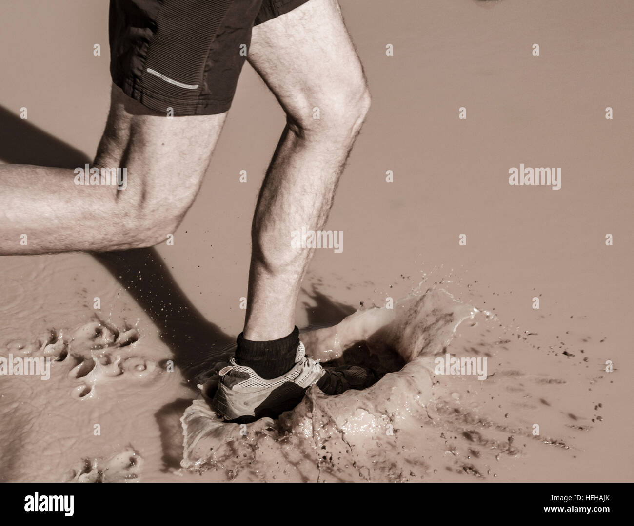Man running through muddy puddle Stock Photo - Alamy