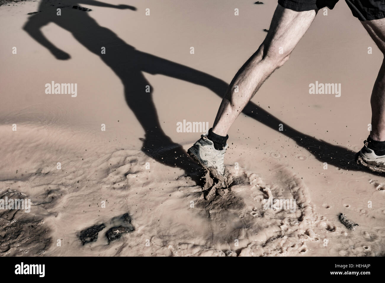 Man running through muddy puddle Stock Photo - Alamy