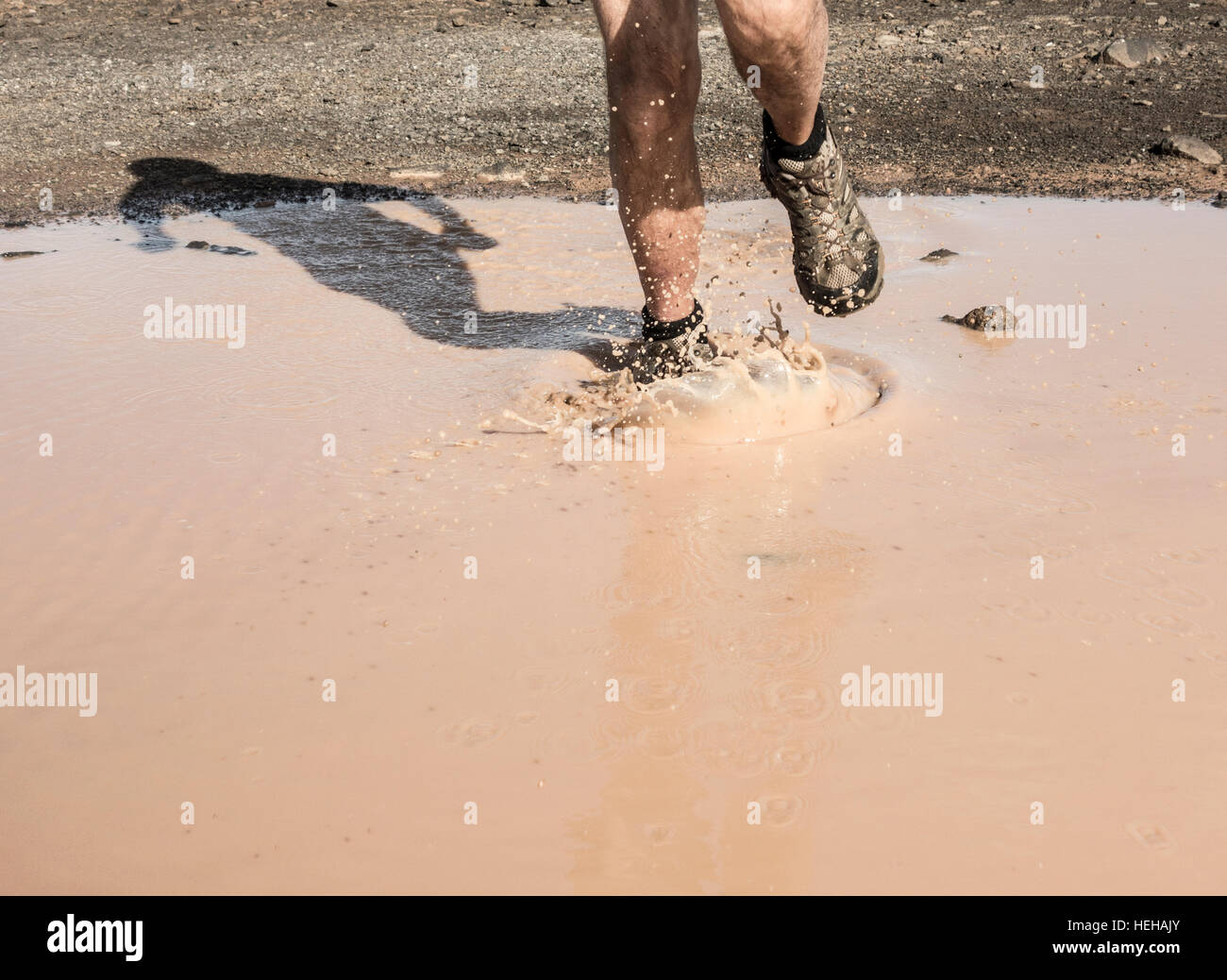Man running through muddy puddle Stock Photo - Alamy