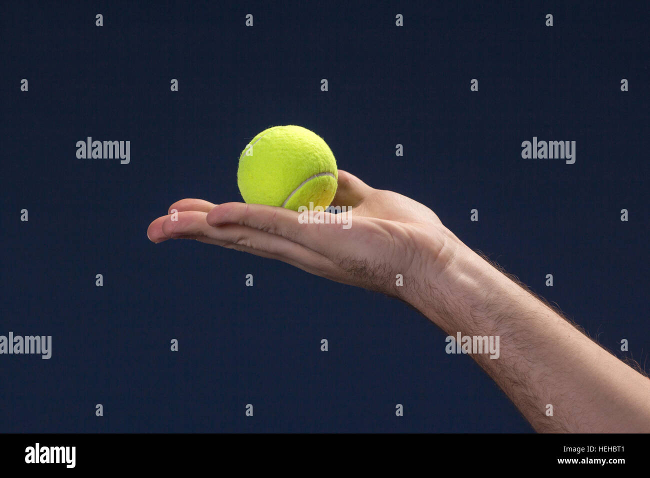 Hand hold Tennis ball on blue background Stock Photo - Alamy