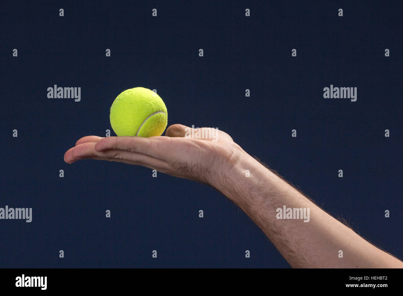 Hand hold Tennis ball on blue background Stock Photo - Alamy