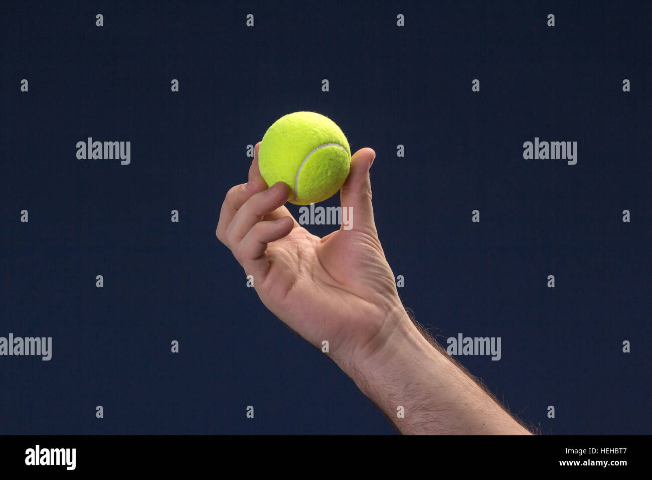 Hand hold Tennis ball on blue background Stock Photo - Alamy