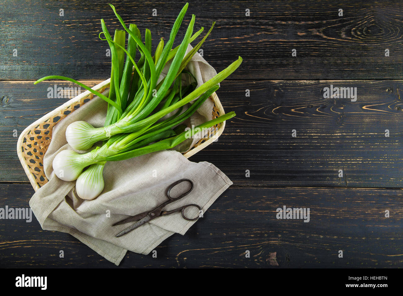 Fresh spring onions and old scissors on a black wooden background Stock ...