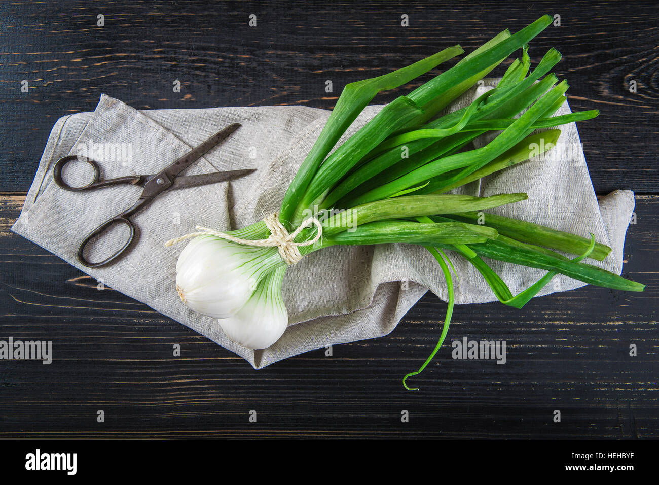 Fresh spring onions and old scissors on a black wooden background Stock ...