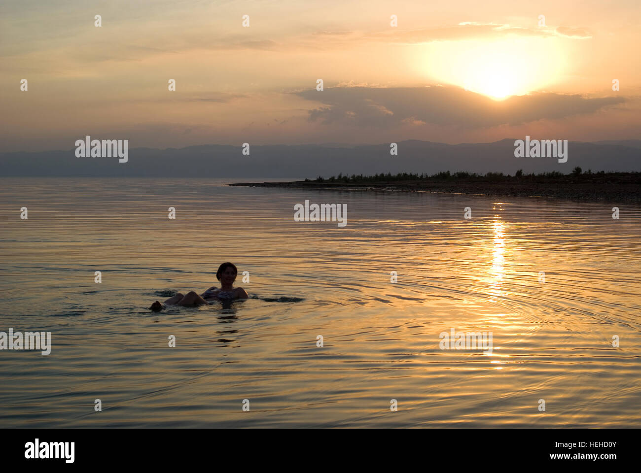 Woman floats in the Dead Sea at sunset, Jordan Stock Photo - Alamy