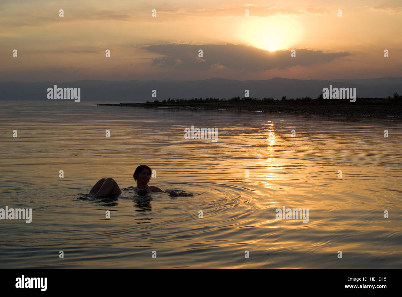 Woman floats in the Dead Sea at sunset, Jordan Stock Photo - Alamy
