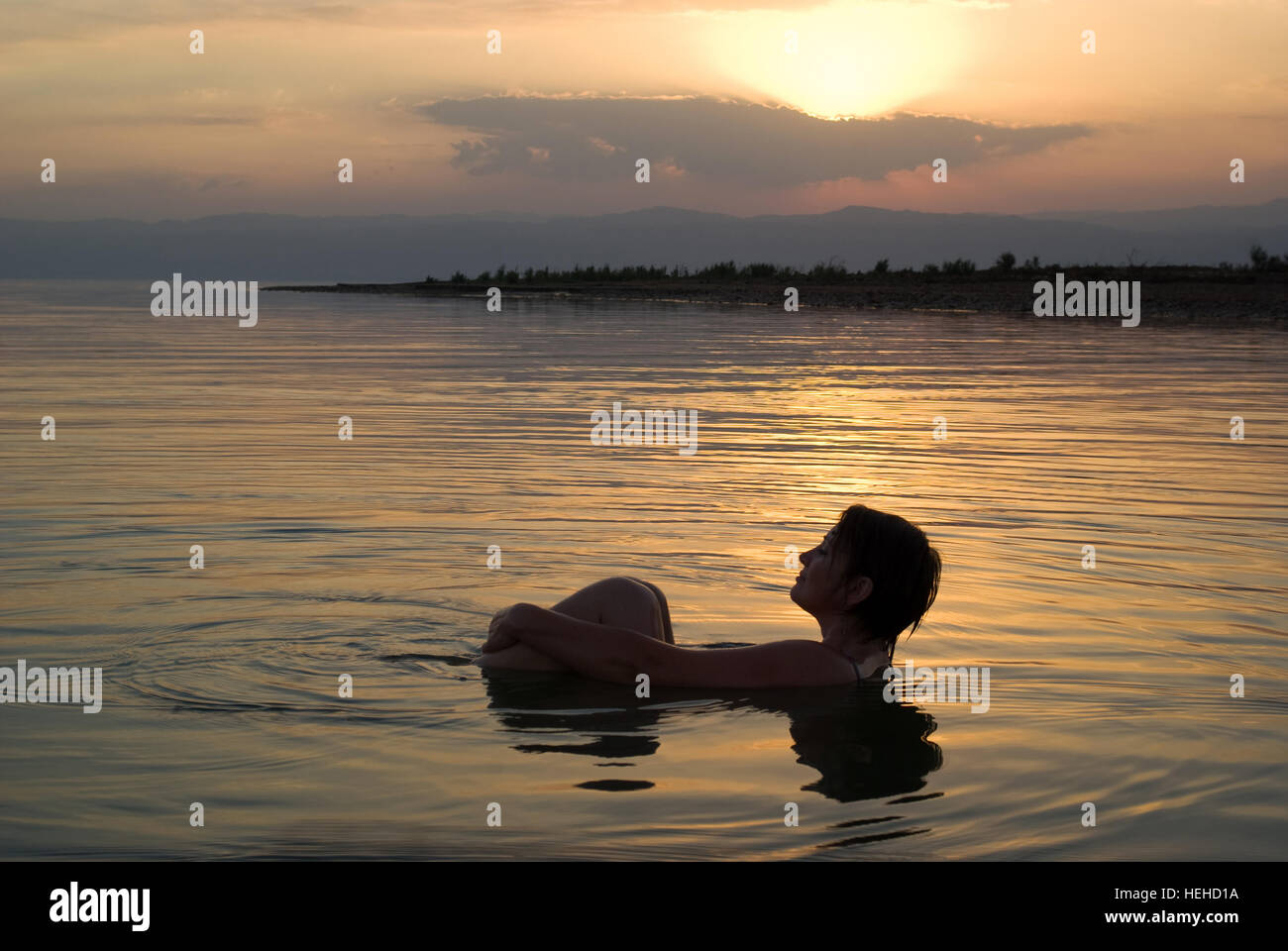 Woman floats in the Dead Sea at sunset, Jordan Stock Photo - Alamy