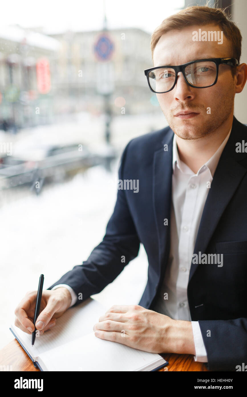 Business specialist writing plan of work and looking at camera Stock ...