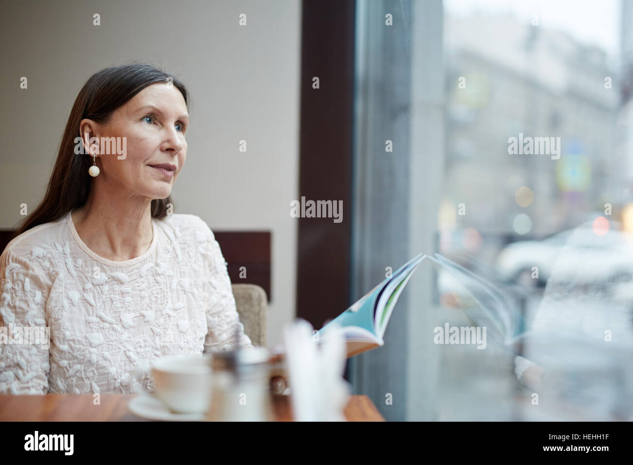 Serene woman with magazine sitting in cafe Stock Photo - Alamy