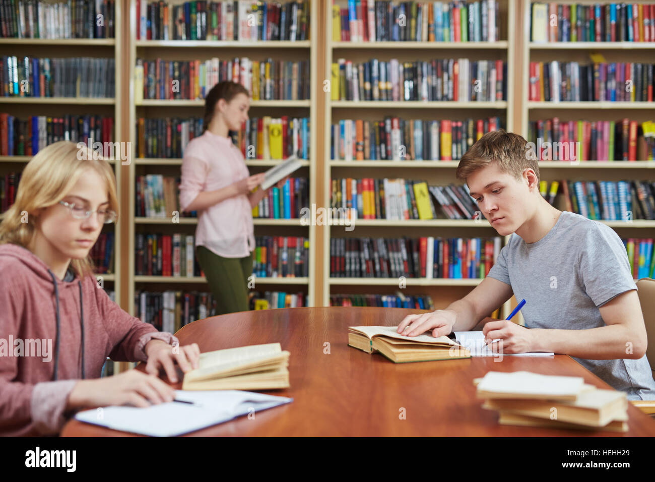 Teenage guy rewriting text from book in library Stock Photo - Alamy