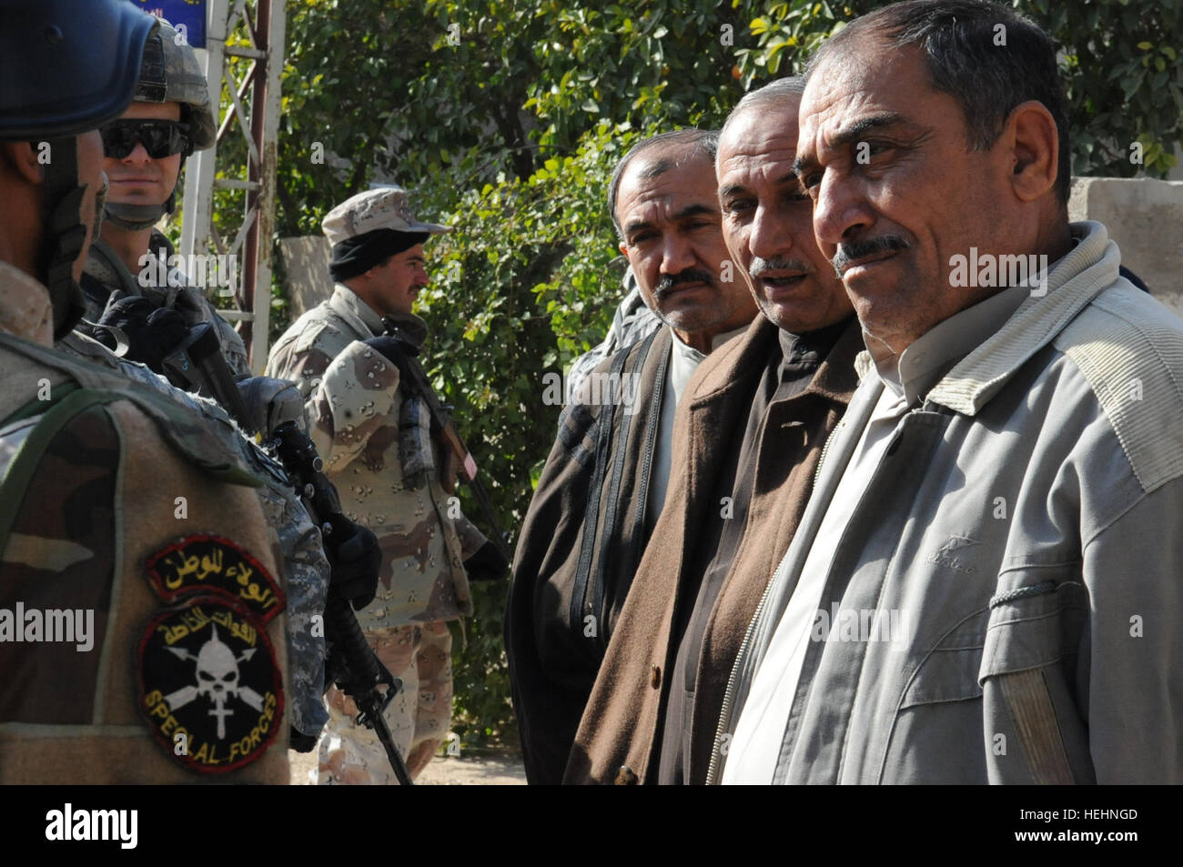 An Iraqi soldier speaks with local Iraqi residents during a joint ...