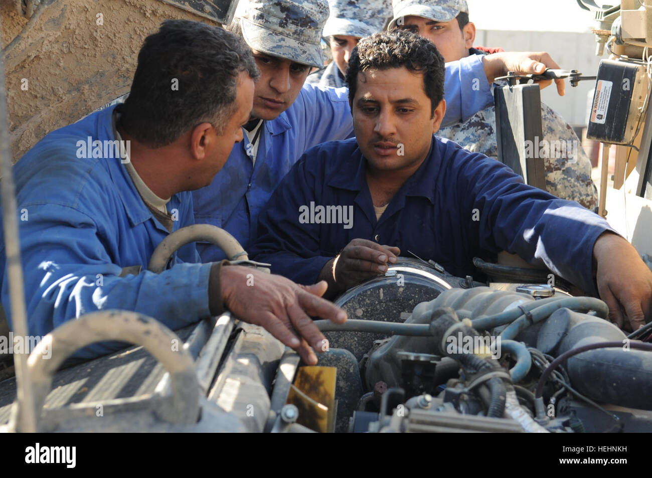 Iraqi national police mechanics examine the engine compartment of a ...