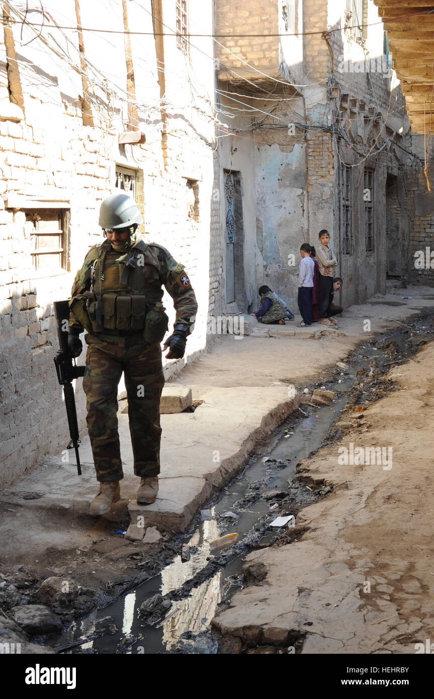 An Iraqi soldier moves down an alleyway while local Iraqi children look ...