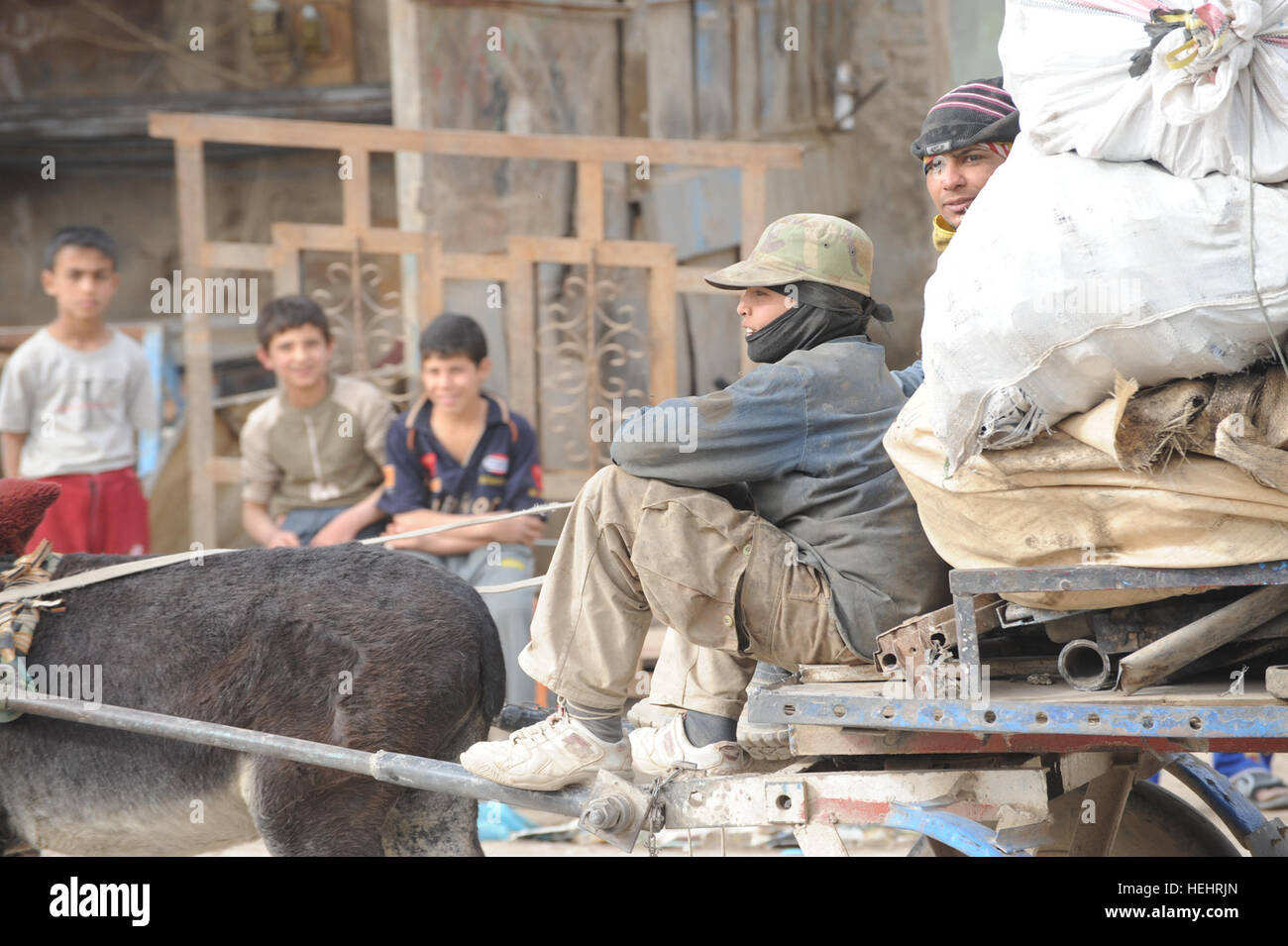 A heavily laden donkey cart passes by Iraqi national police and U.S ...