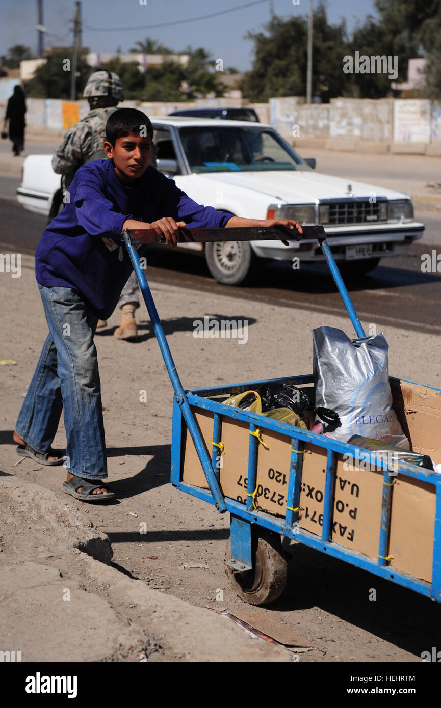 An Iraqi boy pushes a cart with groceries through a market in Baghdad ...