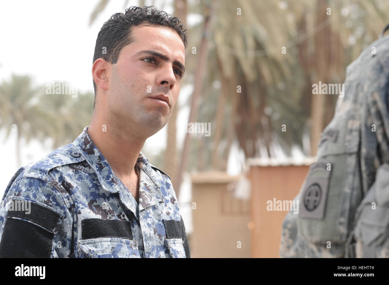 An Iraqi national policeman, manning a checkpoint, listens to U.S ...