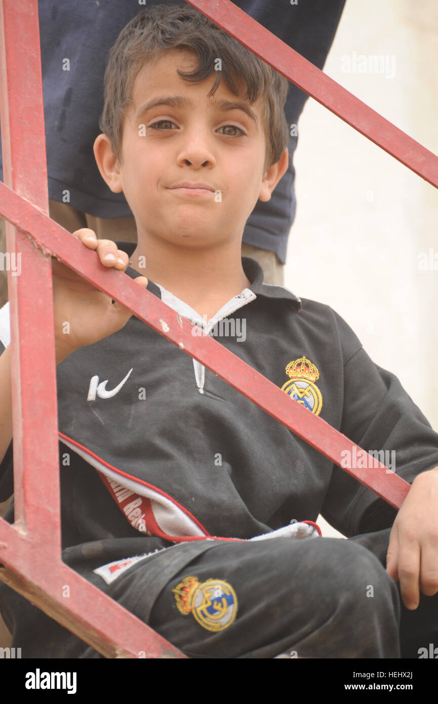 A local Iraqi boy looks at U.S. Soldiers through a stairway railing on ...
