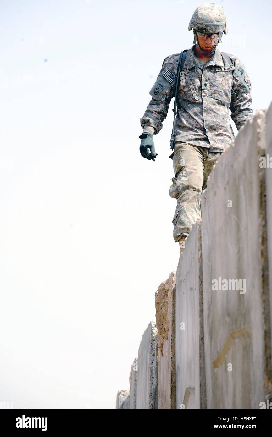 A U.S. Army specialist works atop a concrete barrier to expand T-walls ...