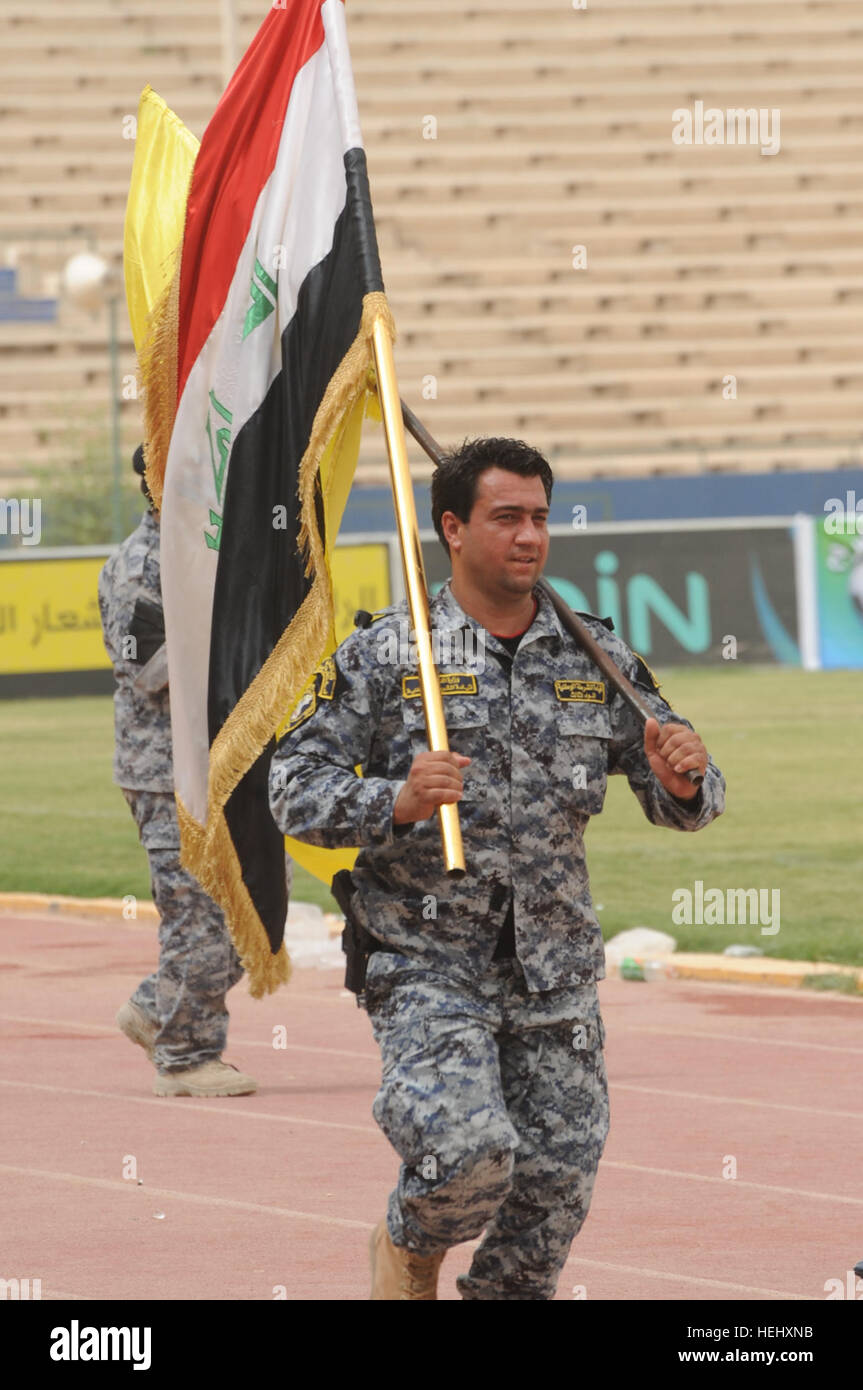 An Iraqi national policeman runs with the Iraqi national flag and a ...