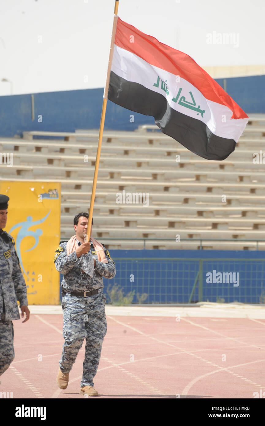 An Iraqi national policeman holds the Iraqi flag high during a ...