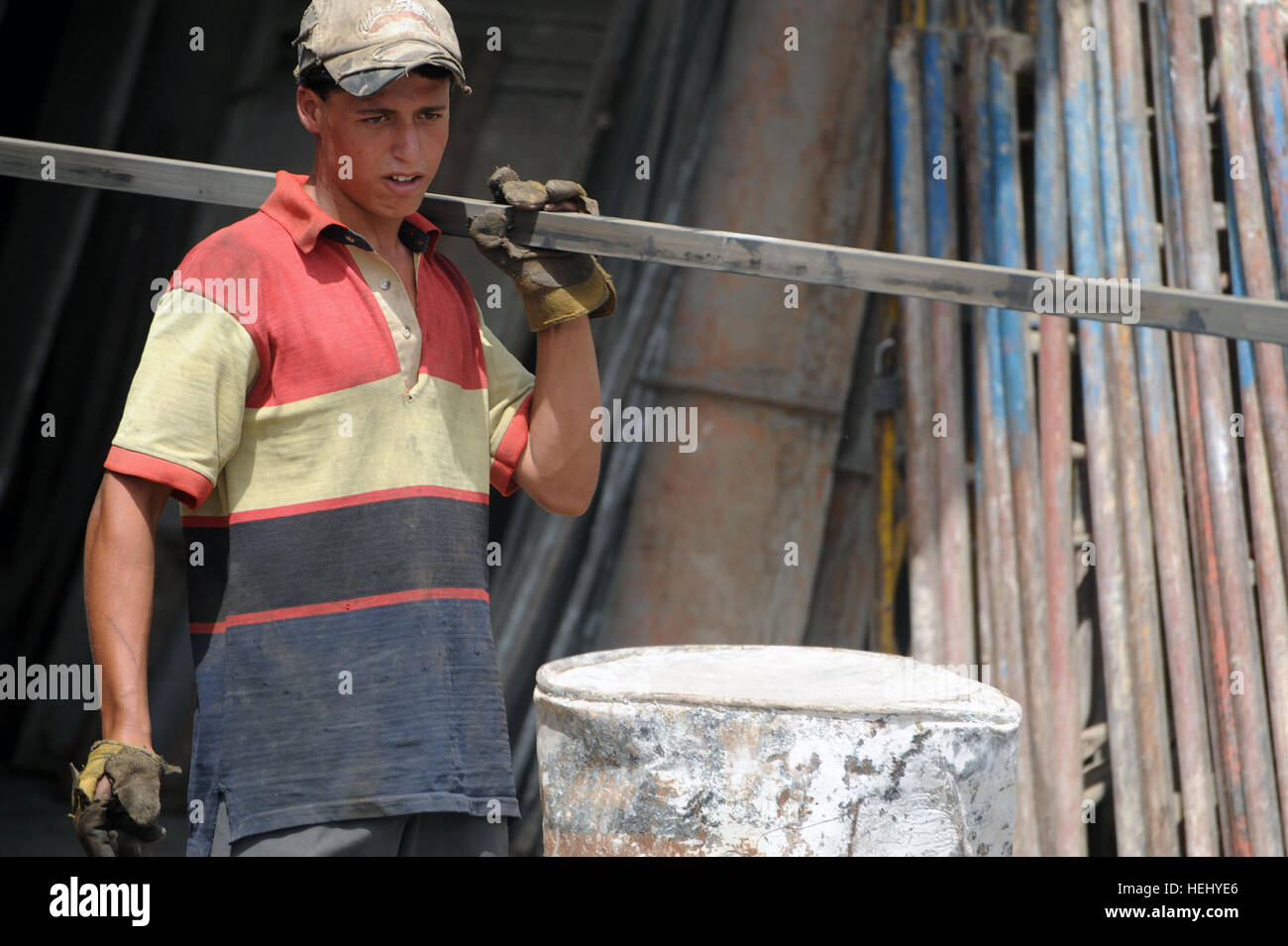 An Iraqi worker carries a metal bar as U.S. Soldiers of 1st Battalion ...