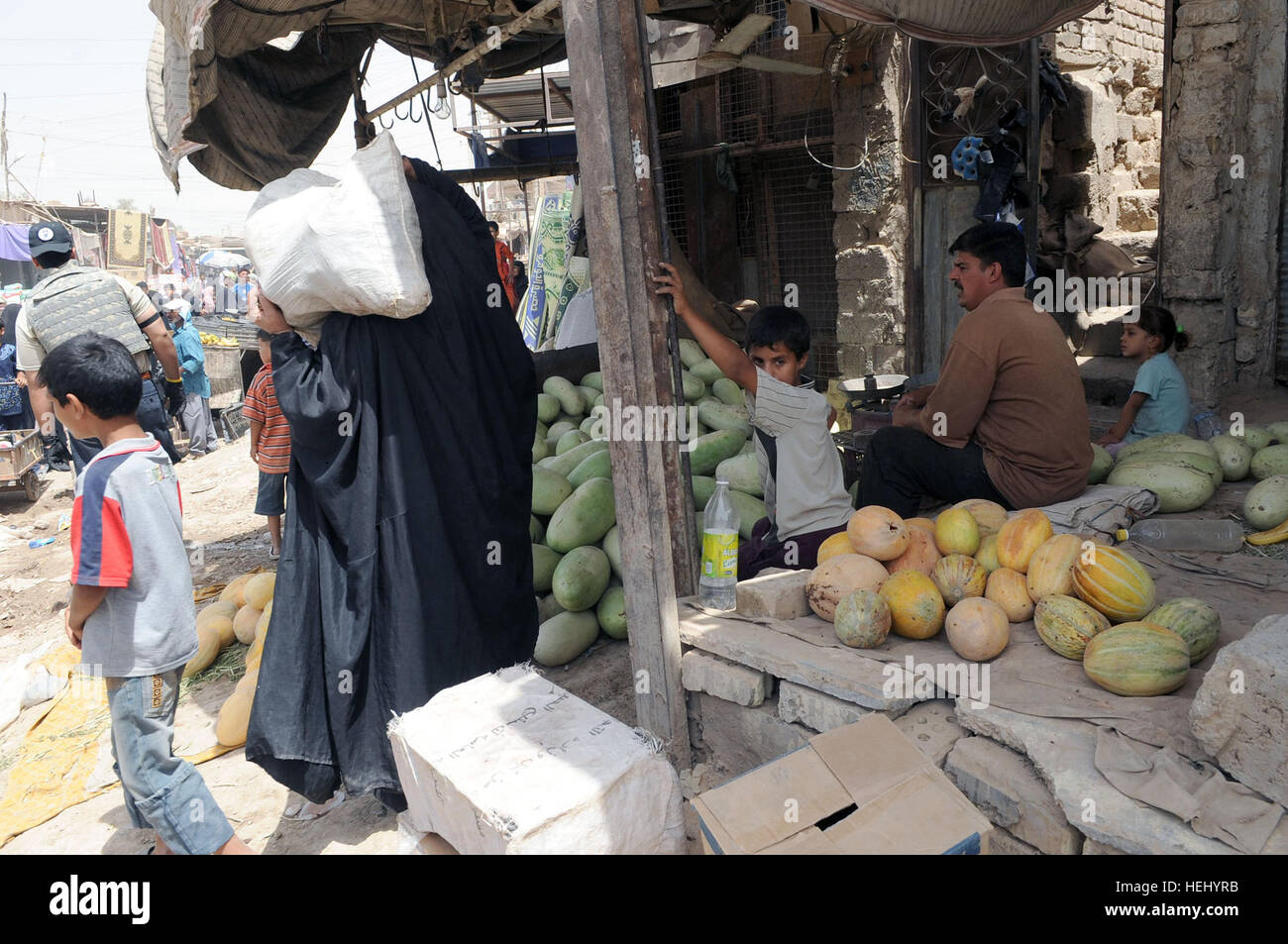 Iraqis operate a street side fruit stand selling melons, on a busy ...