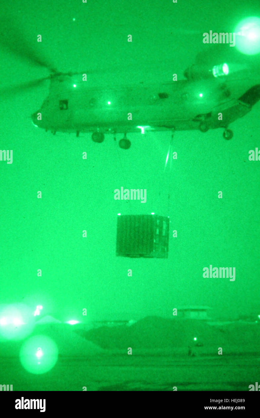 A U.S. Army CH-47 Chinook helicopter carries a sling-loaded container and hovers above the ...
