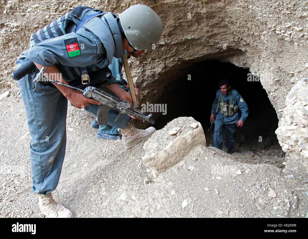 An Afghan national policeman exits a cave after searching it for enemy ...