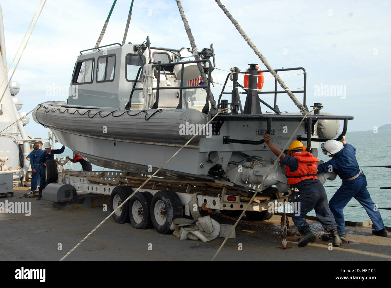 Sailors aboard USS Oak Hill (LSD 51) guide a rigid hull inflatable boat ...