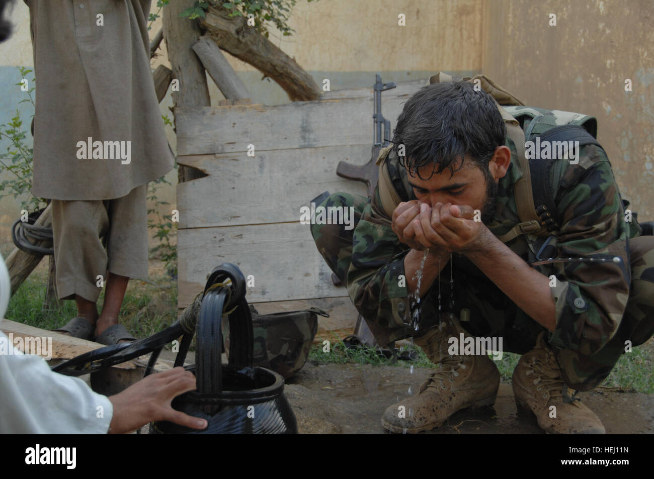 Local children provide water to an Afghan national army soldier during ...