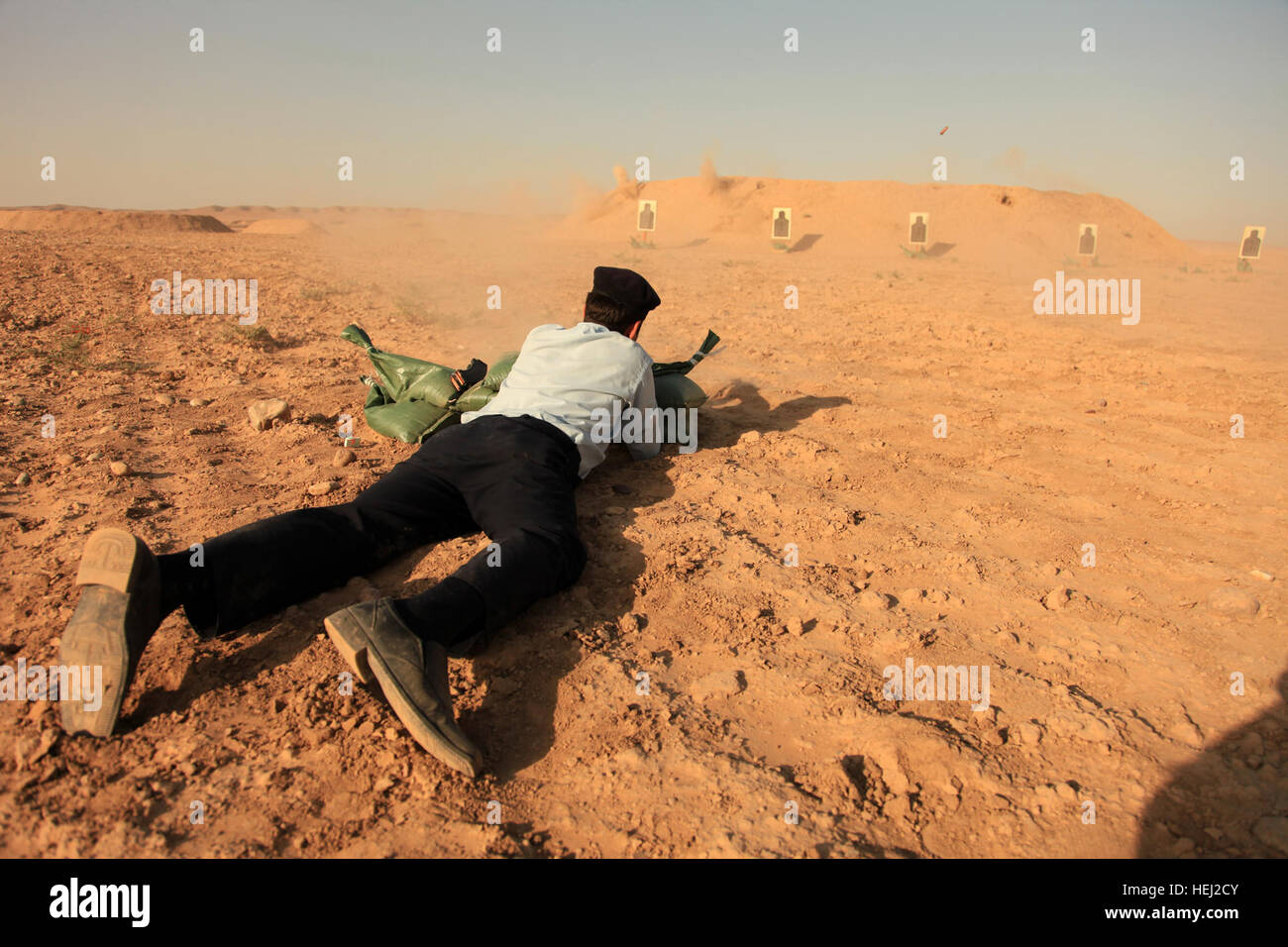 An Iraqi police officer fires his rifle from the prone position during ...