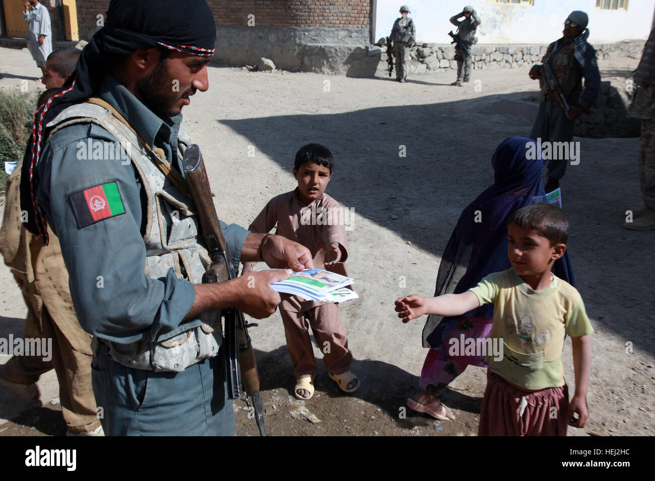 An Afghanistan national policeman hands out a flier, which has a tip ...