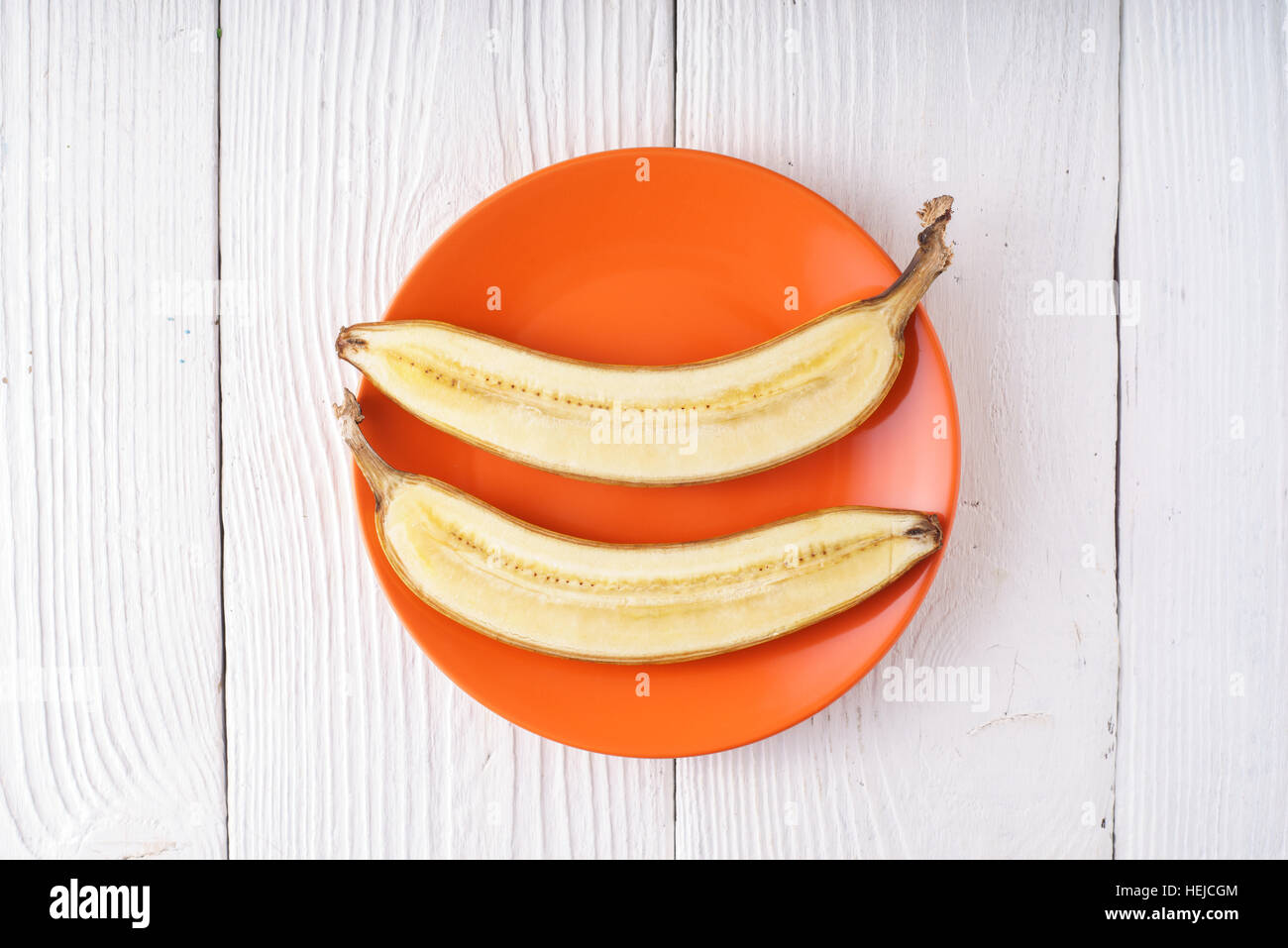Banana halves lie on orange plate horizontal Stock Photo - Alamy