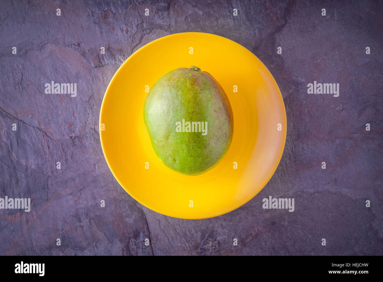 Mango lying on a yellow plate horizontal Stock Photo - Alamy