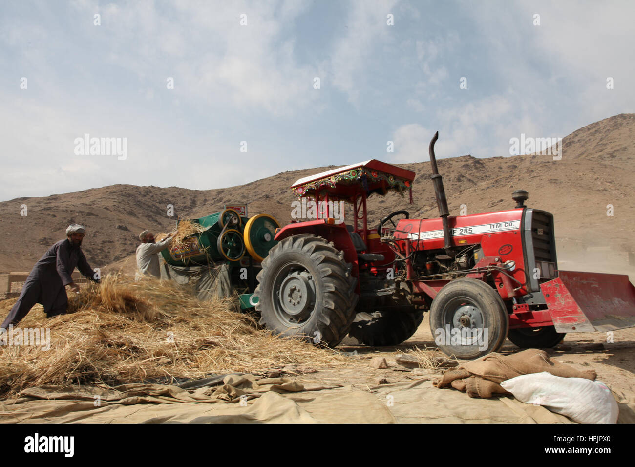 Afghan villagers grind straw while U.S. Marines from Embedded Training ...