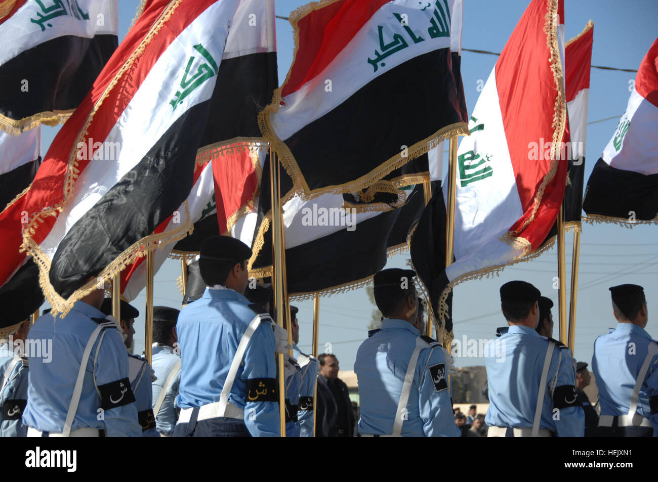 Iraqi police officers march down a street while presenting their nation ...