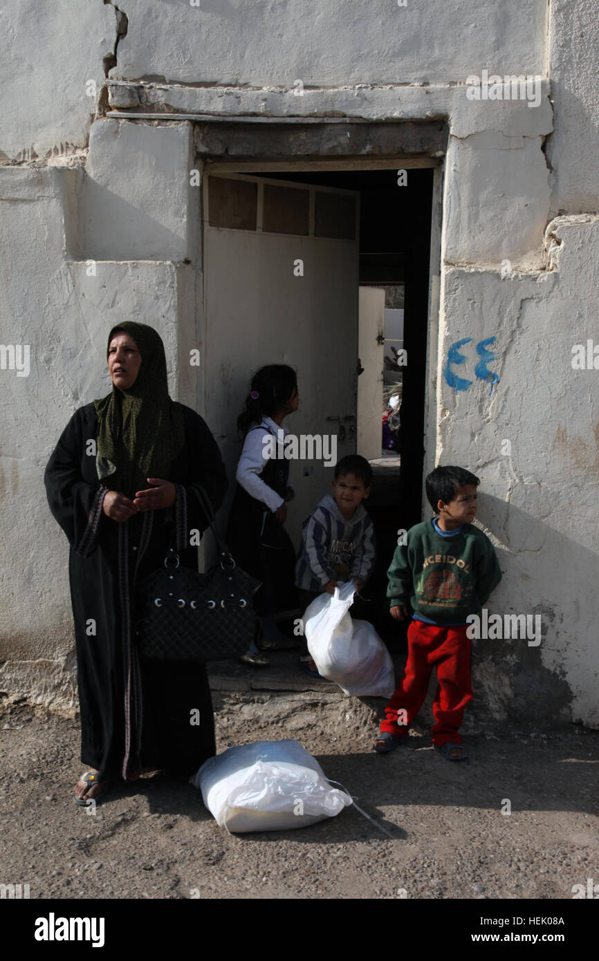 An Iraqi family stands outside their home after receiving food and ...