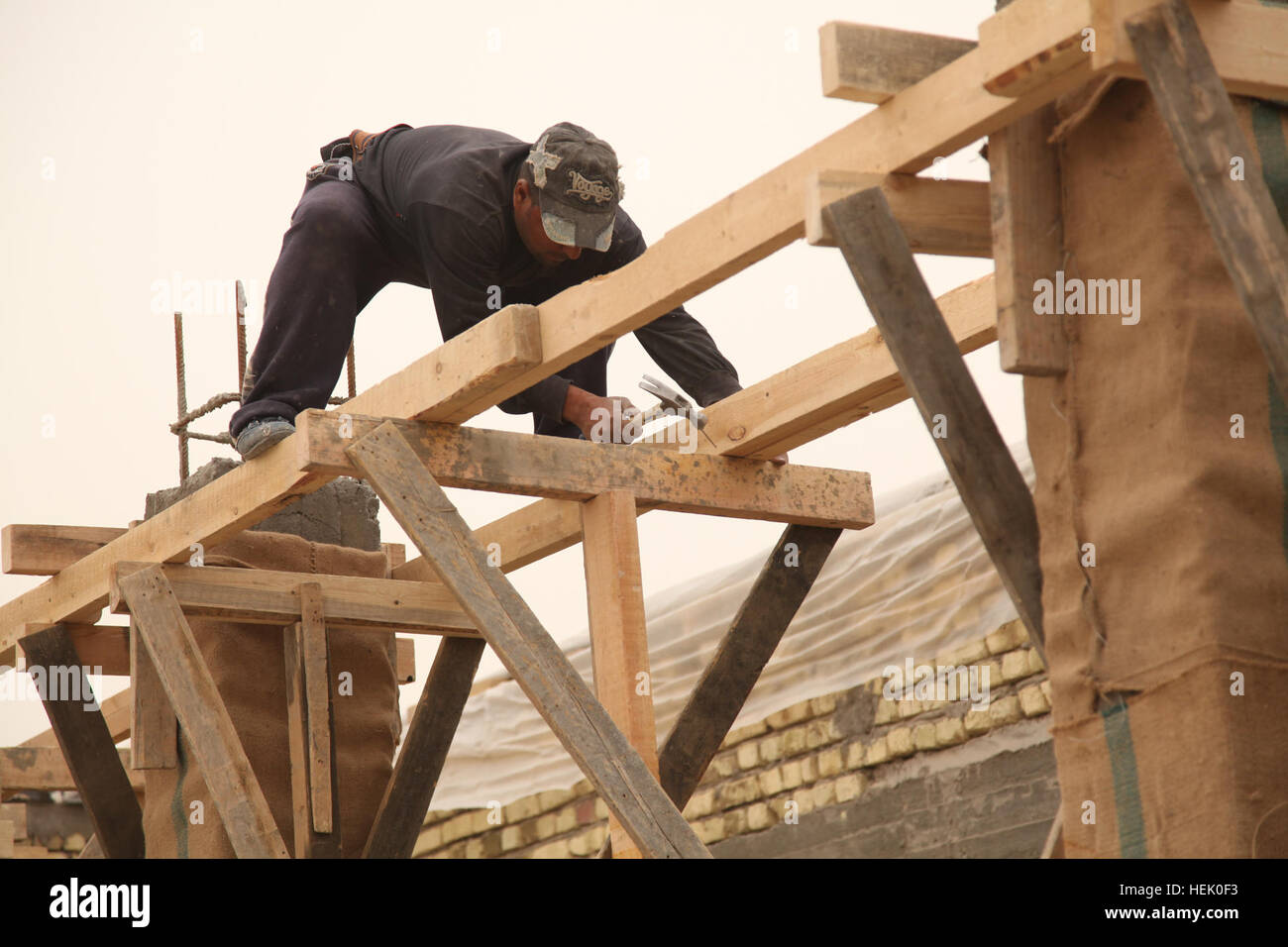 An Iraqi construction worker hammers nails together the frame of a new ...