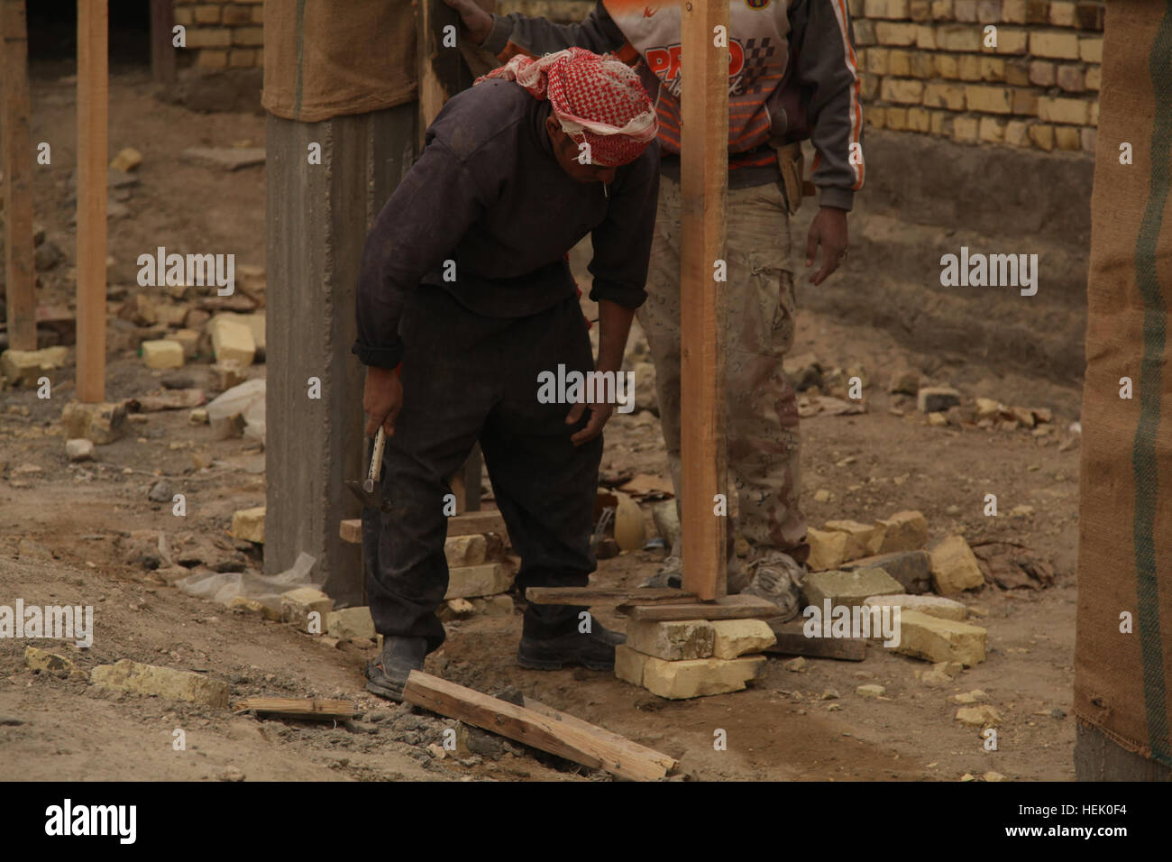 An Iraqi construction worker hammers a piece of wood, creating the ...