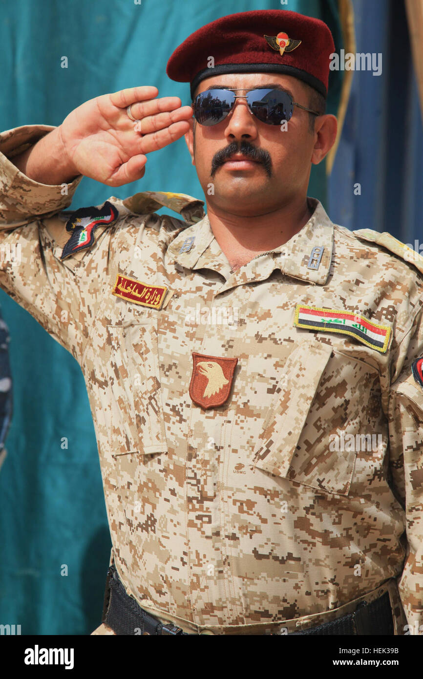An Iraqi police member salutes the Iraqi flag as part of a ceremony ...