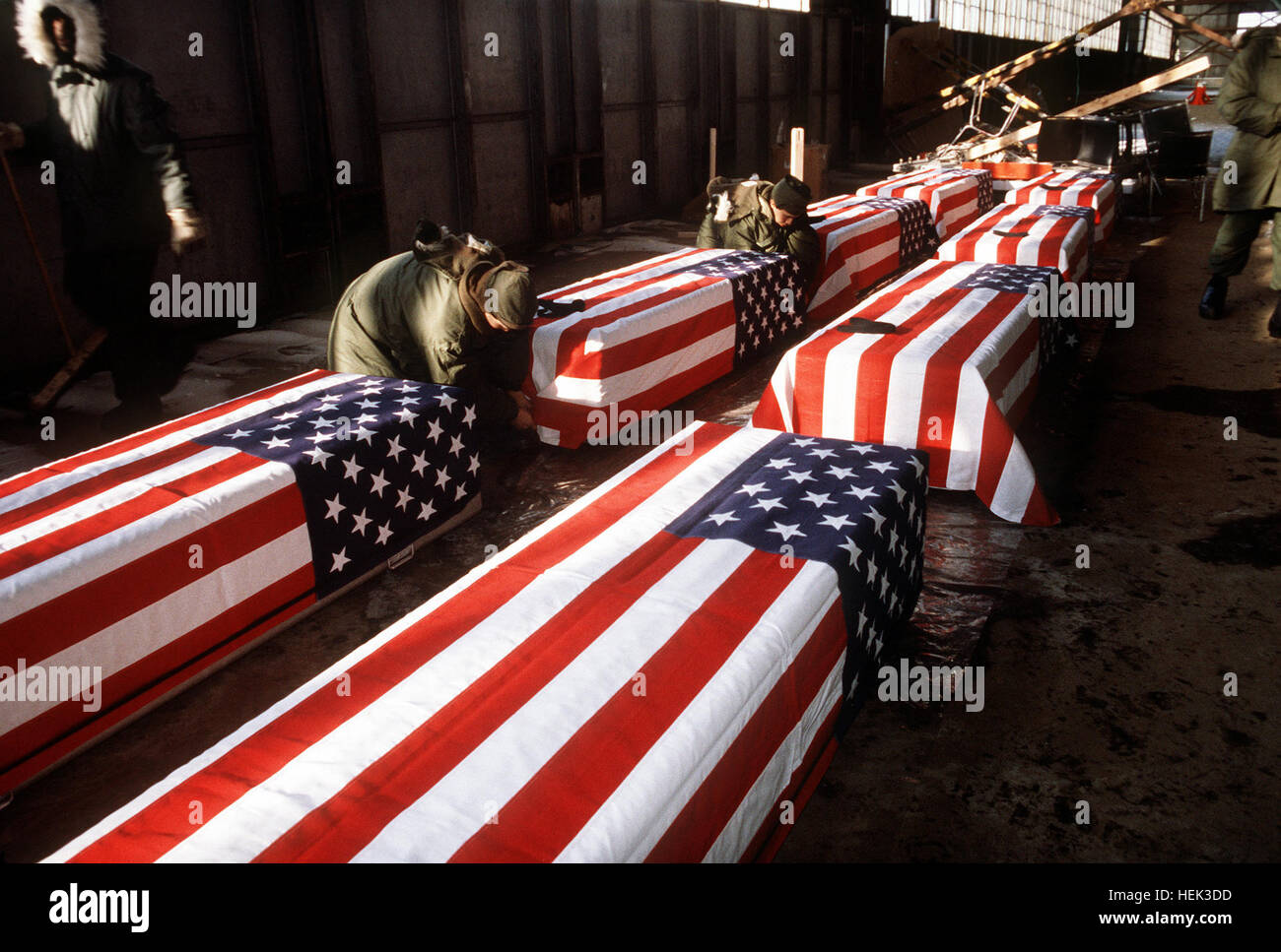 Soldiers fasten flags to caskets containing the remains of members of ...