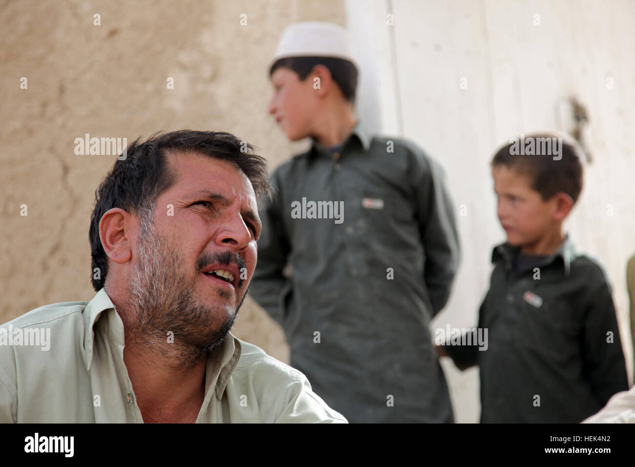 An Afghan man speaks with U.S. Army Soldiers while his children are ...