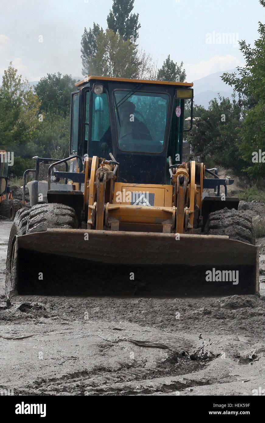 An Afghan construction worker uses a front loader to move mud off a ...