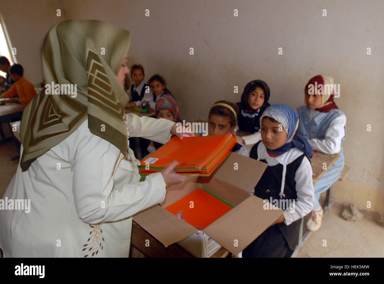 An Iraqi school teacher helps distribute school supplies to Iraqi ...