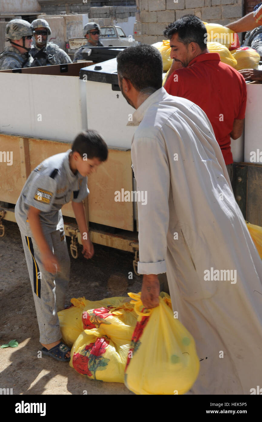 Iraqi men and children unload a truck during an humanitarian aid event ...