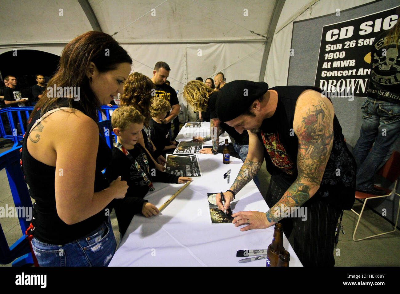 (right to left) Drowning Pool drummer Mike Luce signs an autograph for ...